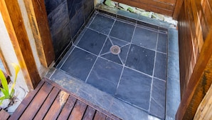 Uma área de chuveiro com porta de madeira e uma pequena prateleira com artigos de higiene pessoal.