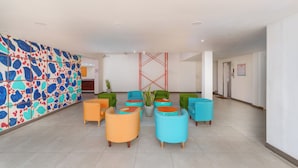 Um hall amplo com assentos coloridos e uma parede vibrante com arte abstrata.
