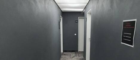 Um corredor estreito com paredes escuras, um tapete estampado e uma porta no final.