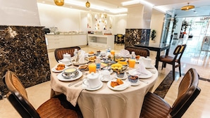 Um buffet de café da manhã com diversos pratos, um espaço para café e uma área de estar com cadeiras e mesa.