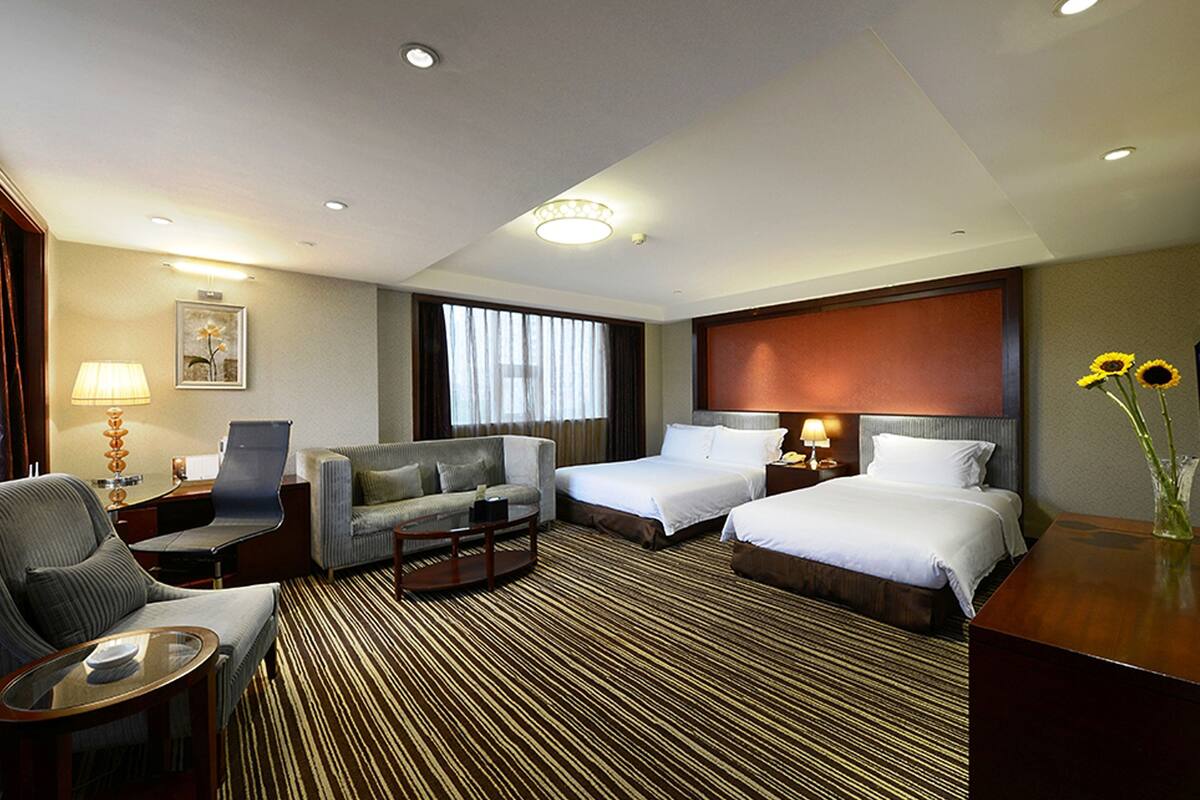 Quarto de hotel com duas camas, um sofá, uma mesa e uma cadeira.