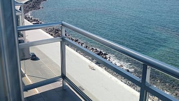 Paisagem costeira com vista clara para o mar, um calçadão e um horizonte distante.