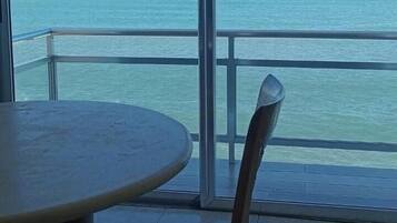 Uma varanda com vista para o mar, uma mesa redonda e uma cadeira.