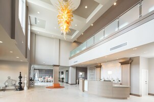 Um hall espaçoso com balcão de recepção, um grande candelabro e teto alto.