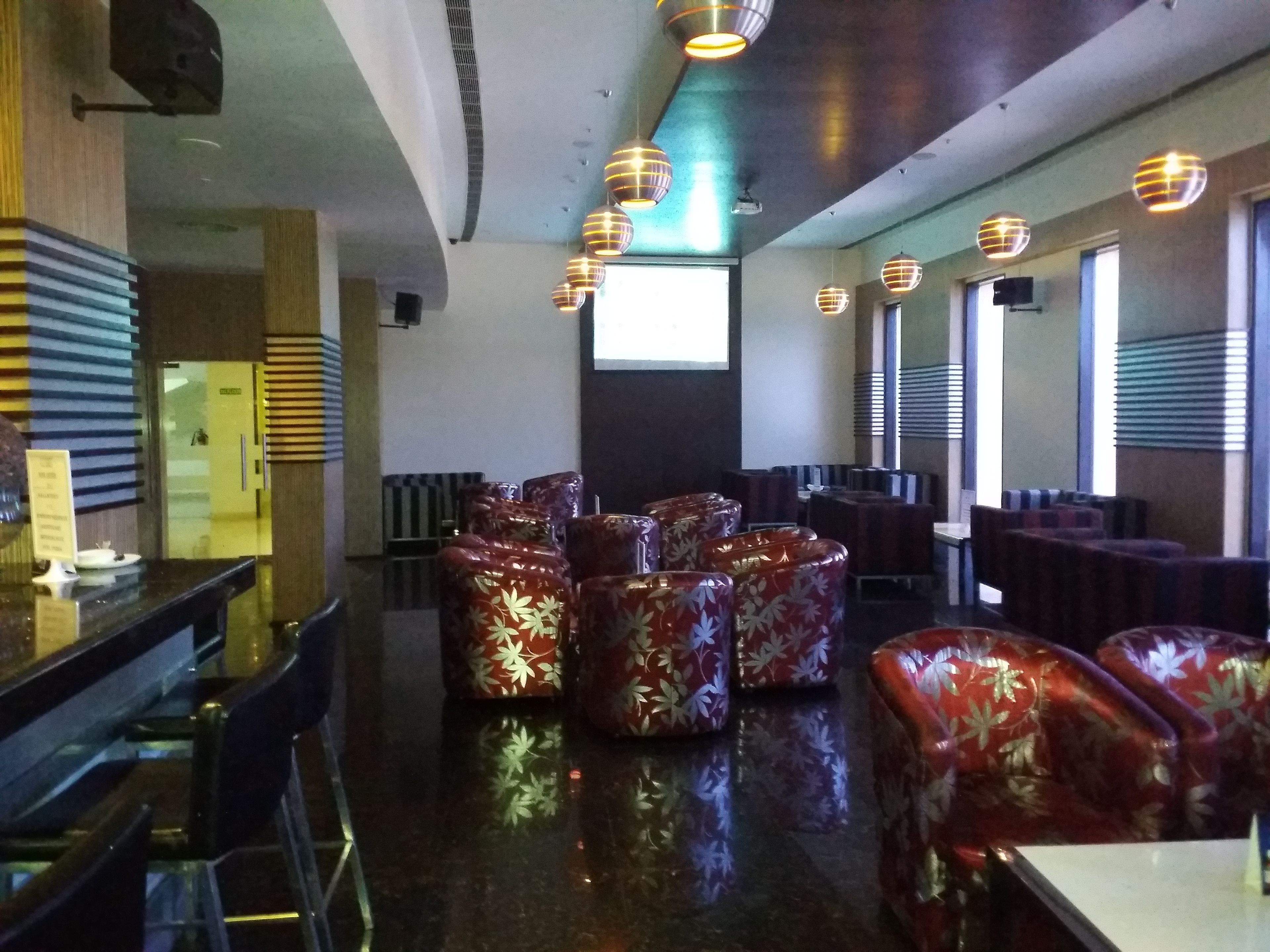 Interior de restaurante com cabines, área de bar e iluminação pendente.