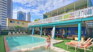 Área de piscina com espreguiçadeiras e um edifício com varanda.