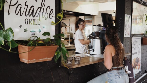 Um restaurante chamado 'Surfers Paradise Grill' com uma decoração de prancha de surf e uma máquina de café.