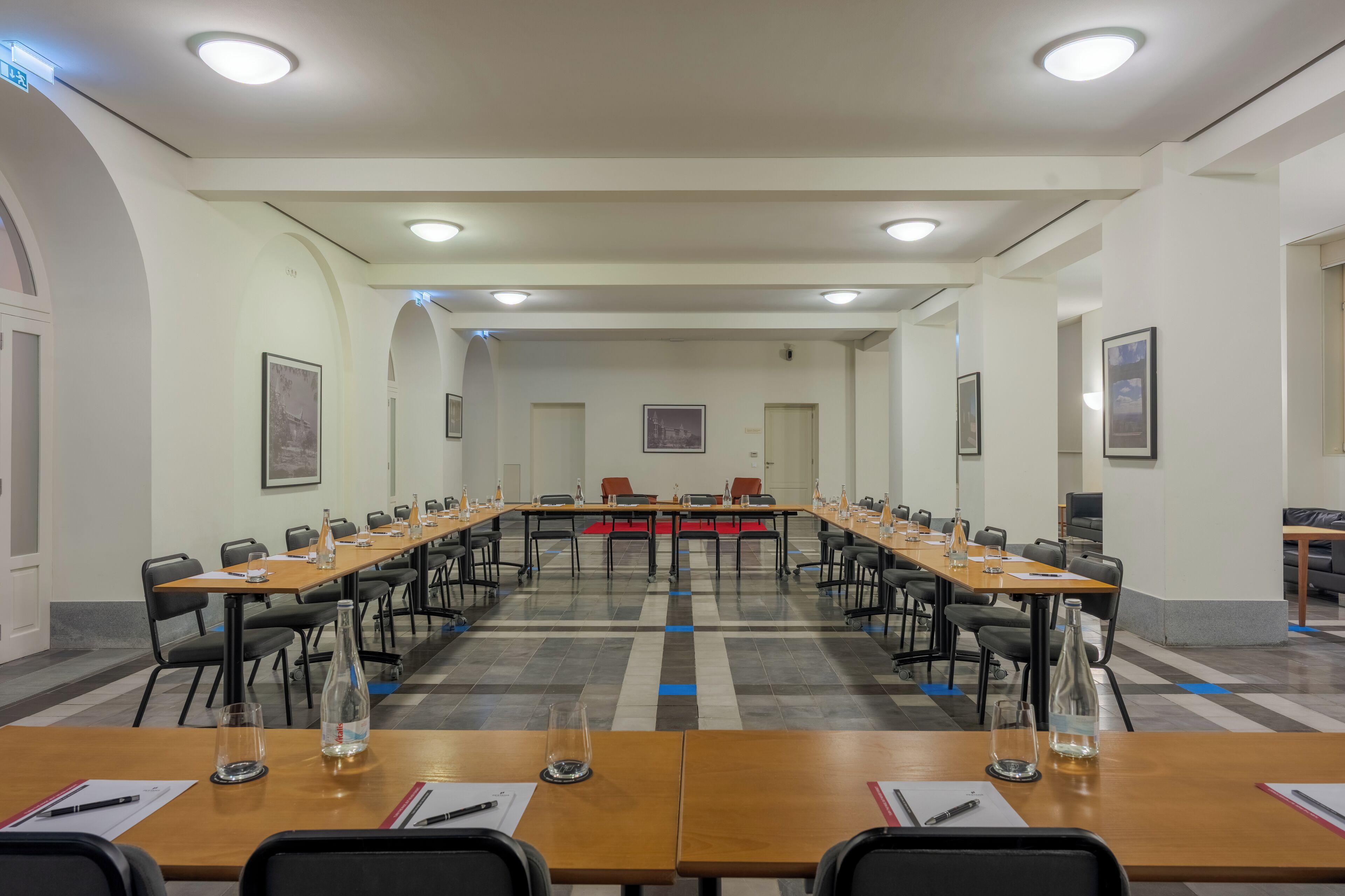 Uma sala de conferências com uma mesa comprida, cadeiras e um tapete vermelho.