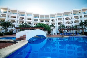 Hotel com piscina, várias varandas e área de estar coberta.