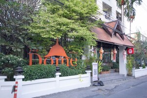 Entrada de hotel com um grande letreiro 'Home', um alpendre coberto e uma placa de 'Proibido Entrar'.