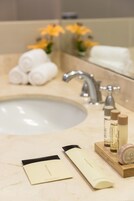 Casa de banho com lavatório, produtos de higiene e toalhas.