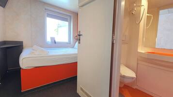 Quarto de hotel com cama, janela, sanita e área de duche.