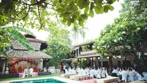 Espaço para casamento junto à piscina, com palco, assentos e vegetação exuberante.
