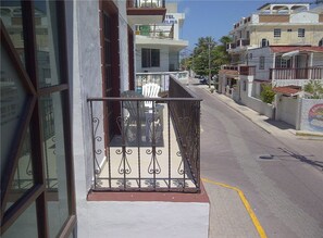Varanda com guarda-corpo de metal e vista para uma rua com edifícios.