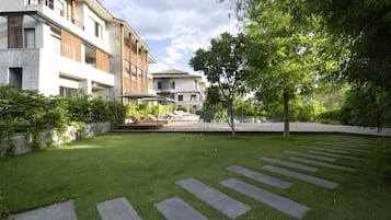 Um edifício residencial moderno com um gramado bem cuidado, piscina e céu limpo.