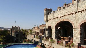 Um edifício com estilo de castelo e uma piscina em frente.