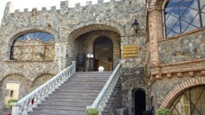 Um edifício de pedra com escadaria que leva a uma entrada, janelas em arco e um poste de lanterna.