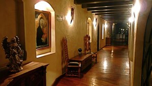 Um corredor de madeira com um banco, uma estátua e um quadro na parede.