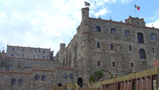Um edifício de pedra histórico com várias janelas e uma bandeira.