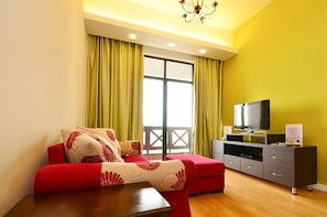 Uma sala de estar moderna com um sofá vermelho, uma TV em um móvel cinzento e cortinas verdes.
