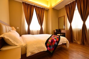 Quarto de hotel com cama, escrivaninha e espelho.
