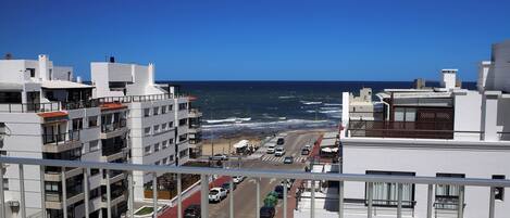 Paisagem costeira urbana com edifícios modernos, uma praia e céu azul límpido.