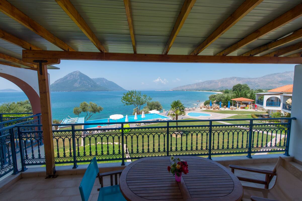 Uma varanda com vista para uma piscina, uma montanha e o mar.