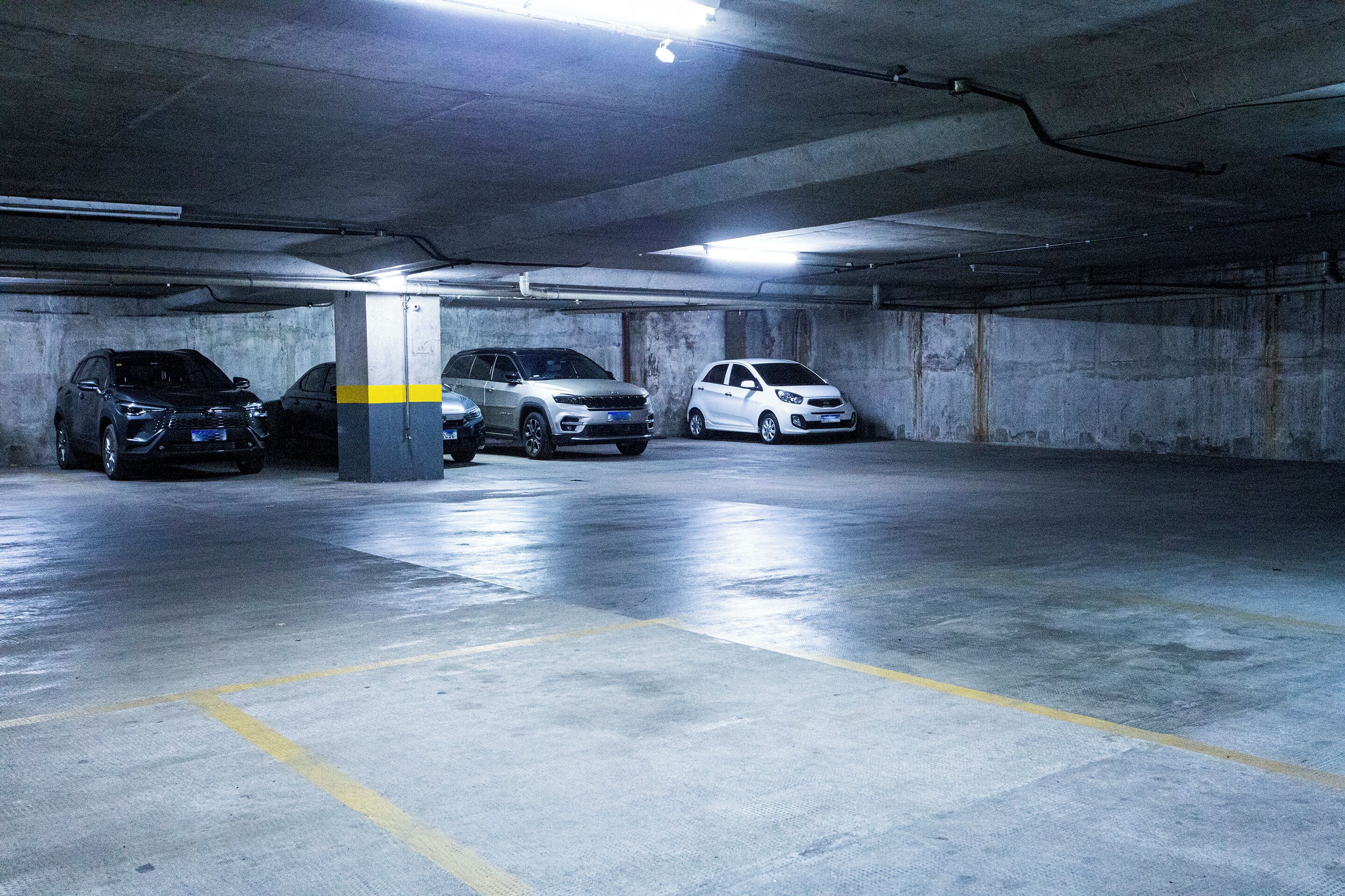 Uma garagem de estacionamento com três carros estacionados em fila.