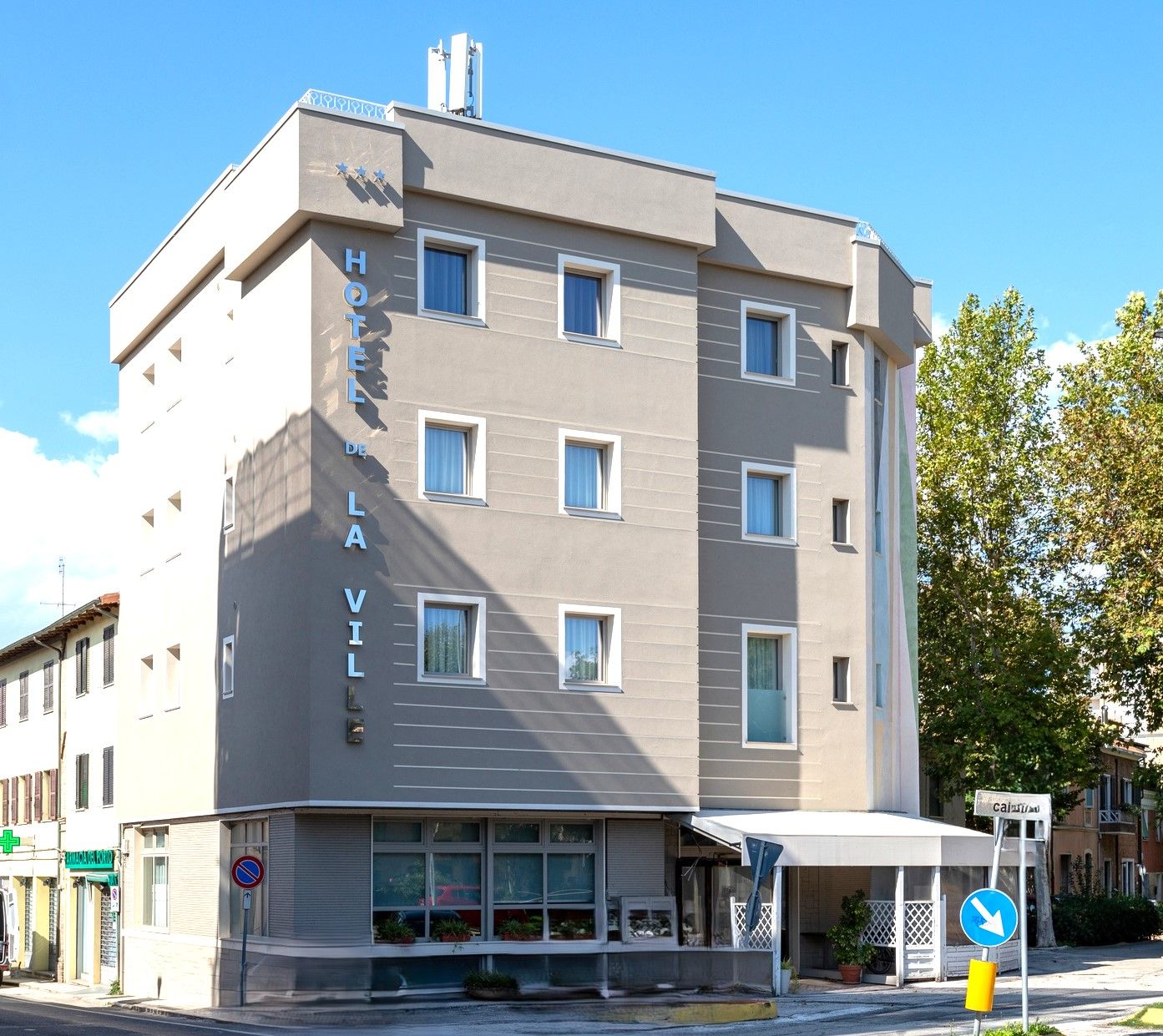 Um hotel com vários andares, fachada plana, várias janelas e área de entrada coberta.