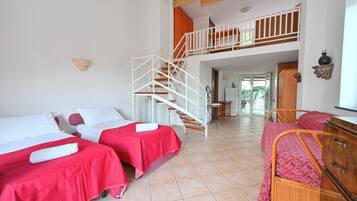 Quarto de hotel com duas camas, penteadeira de madeira, escada e vista para o exterior.
