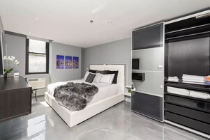 Quarto moderno com uma cama grande, uma escrivaninha e um closet espaçoso.
