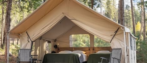 Acomodação em tenda com duas camas, uma mesa e cadeiras.