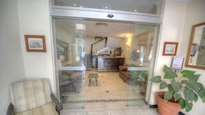 Um saguão de hotel com balcão de recepção, escada e área de estar.