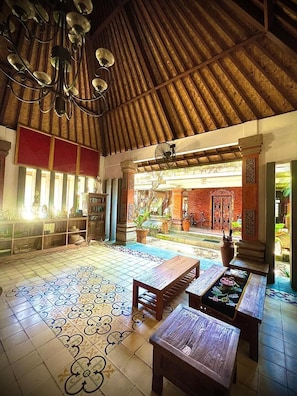 Um quarto espaçoso com teto alto, teto de madeira, uma janela grande e uma mesa com cadeiras.
