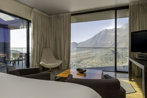 Quarto de hotel moderno com uma varanda ampla, televisão de tela plana e vista para montanhas.
