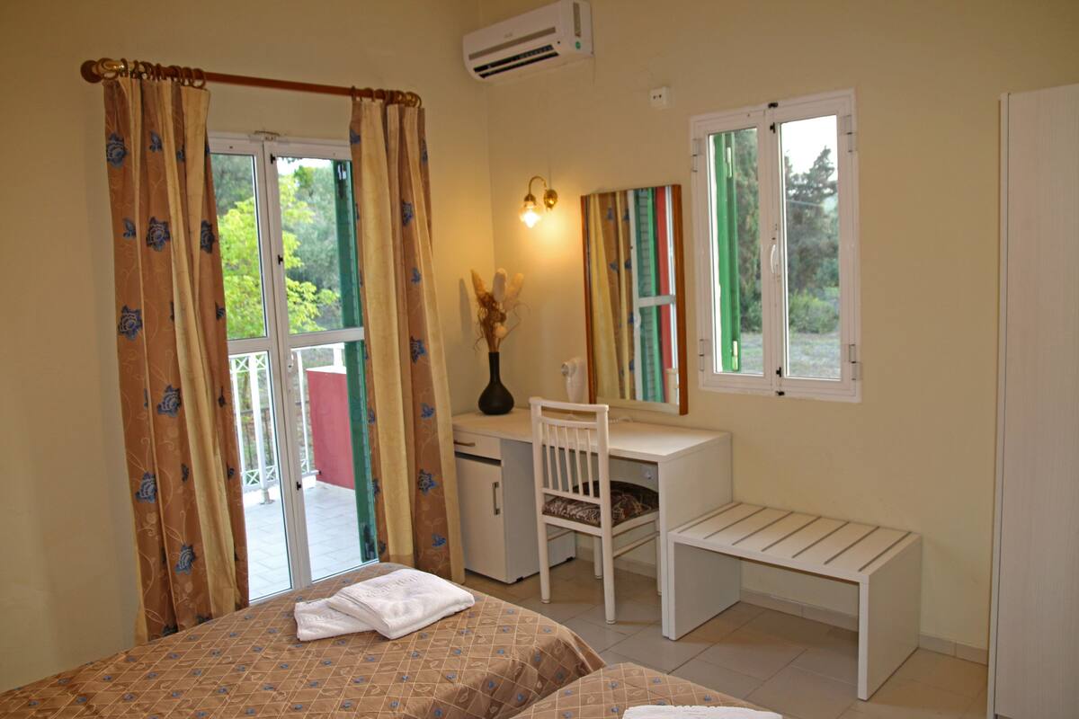 Um quarto com cama, escrivaninha, cadeira e um banco.