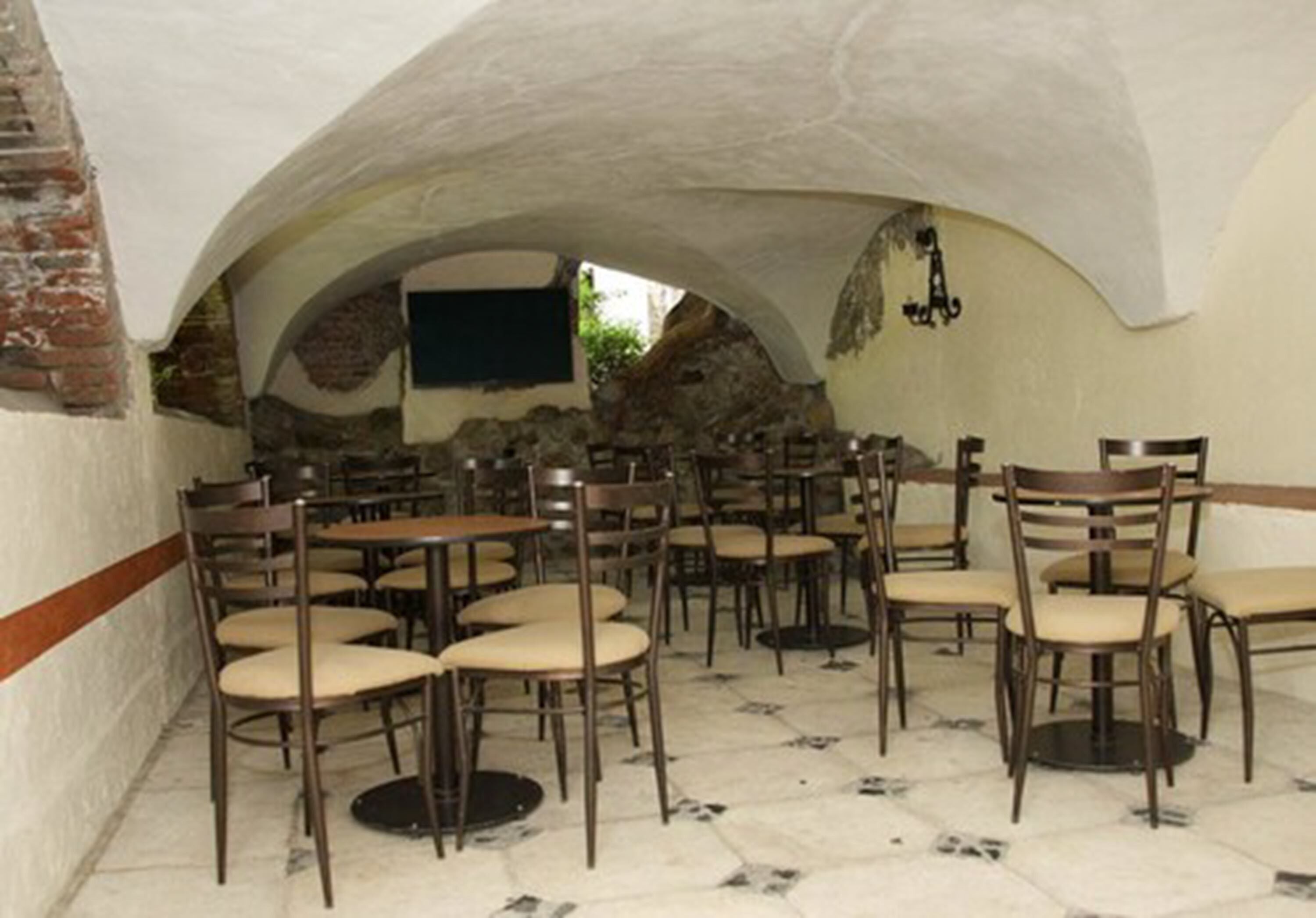 Um espaço de refeições subterrâneo com paredes de pedra, mesas e cadeiras de madeira.