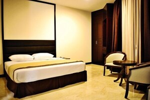 Quarto de hotel com uma cama grande, uma mesa e uma cadeira.