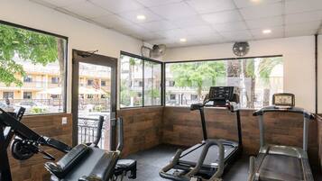 Uma academia com esteiras, uma bicicleta ergométrica e um banco de musculação.