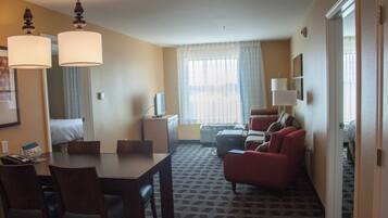 Quarto de hotel com mesa de jantar, cadeiras, sofá e televisão.