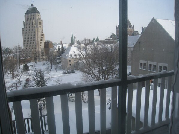Vista de uma cidade coberta de neve, com um edifício imponente e uma igreja.