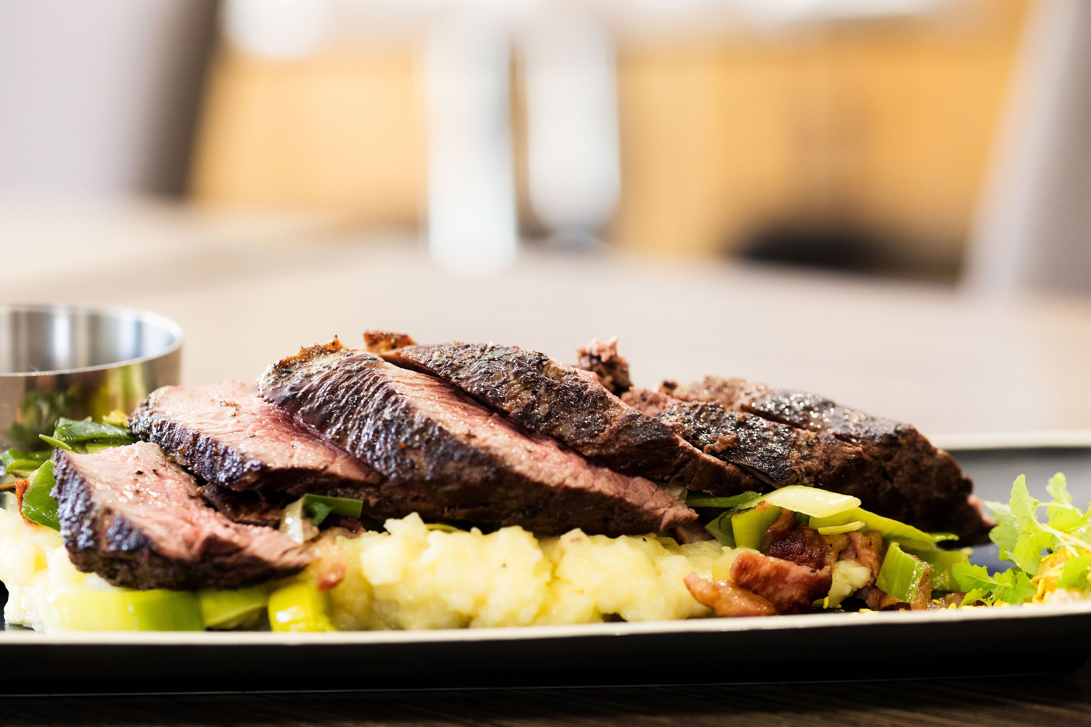 Um prato de bife fatiado com legumes e batatas.