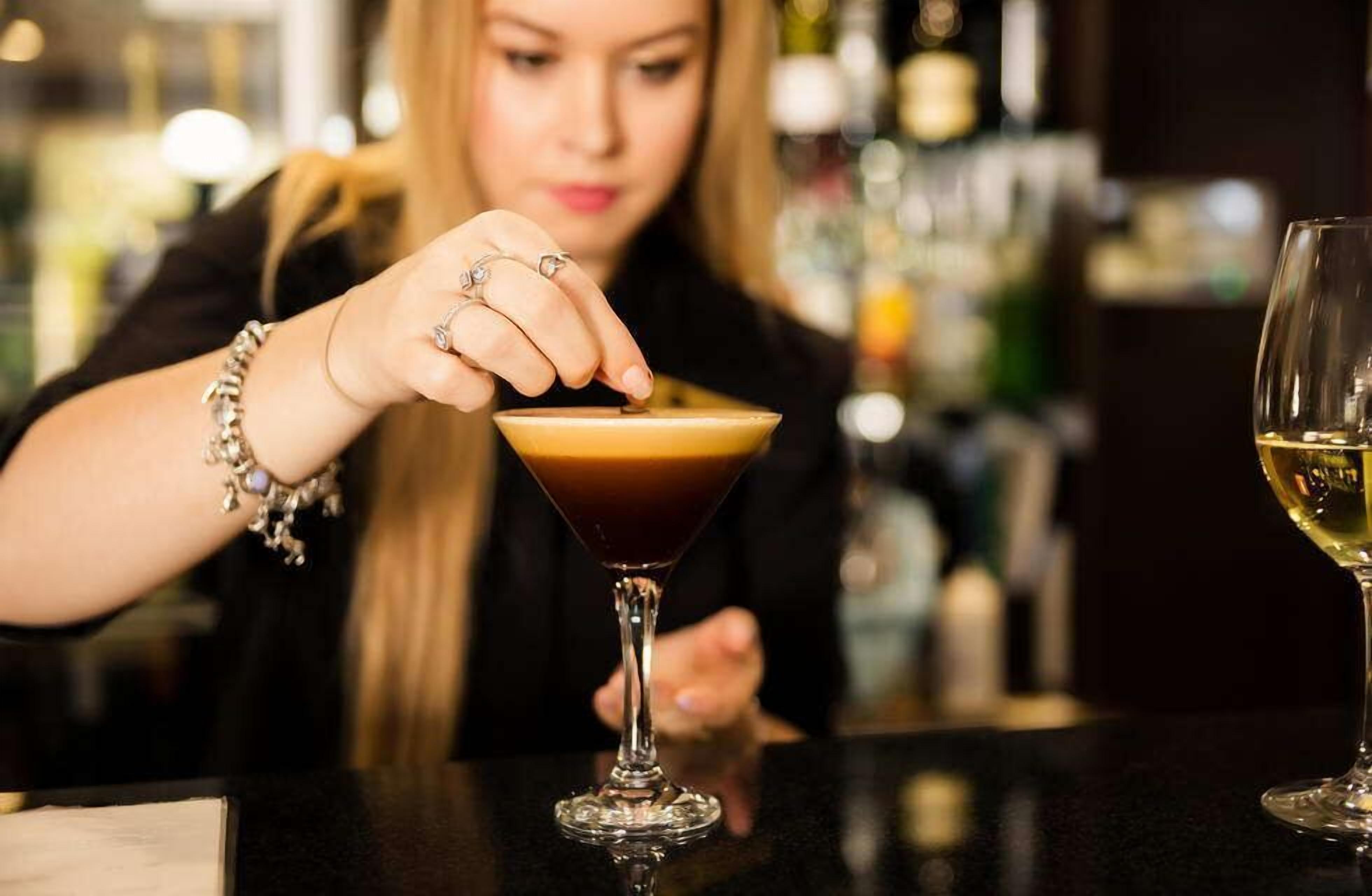 Alguém servindo uma bebida em uma taça martini.