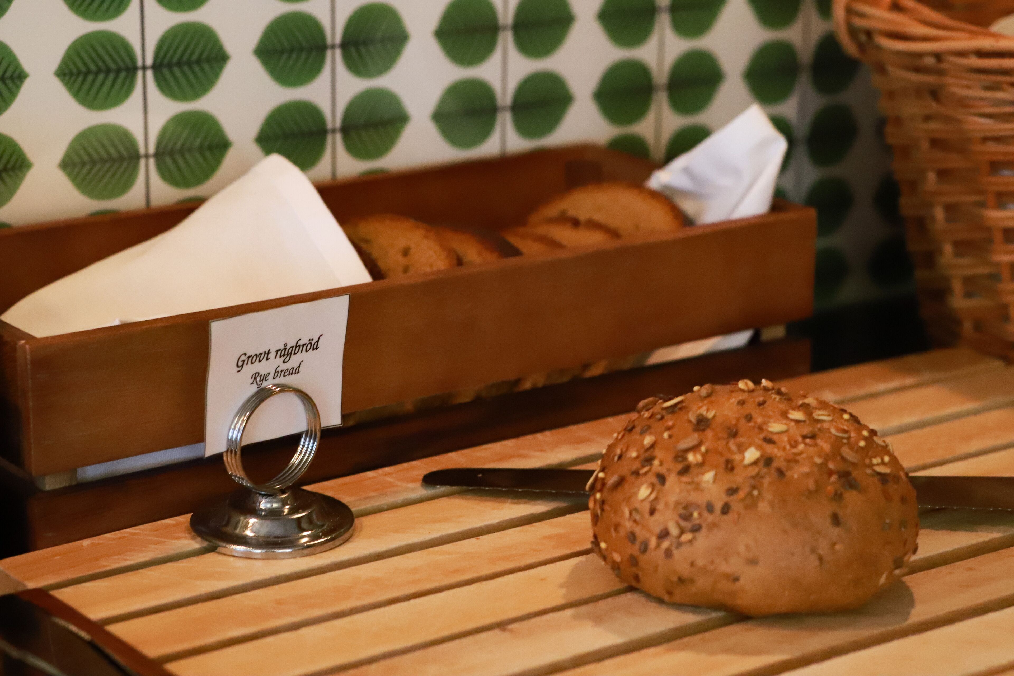 Uma mesa de madeira com um pão e uma placa indicando 'Grøtt røgbrød Rye bread'.