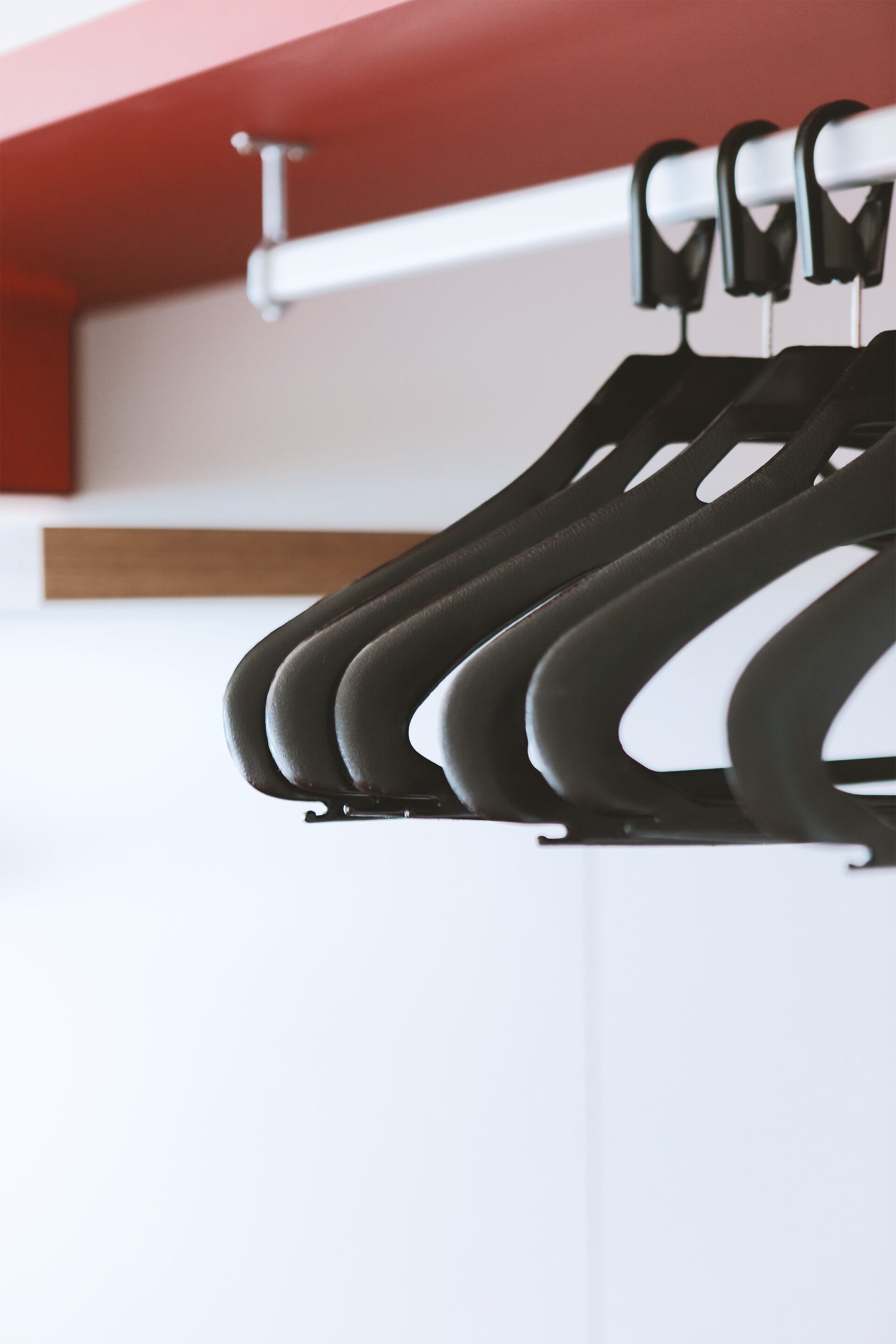 Uma fileira de cabides pretos em um suporte de metal branco.