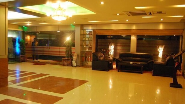 Um hall com lustre, balcão de recepção e área de estar.