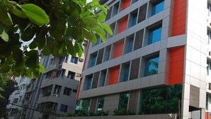 Um edifício residencial de vários andares com design arquitetônico moderno, com varandas e janelas amplas.