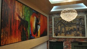 Quarto com uma grande pintura abstrata na parede, um candelabro e um mural com arte tradicional.