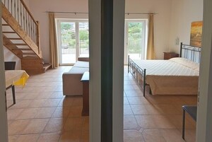 Um quarto com uma cama, um banco, uma mesa e uma escada.