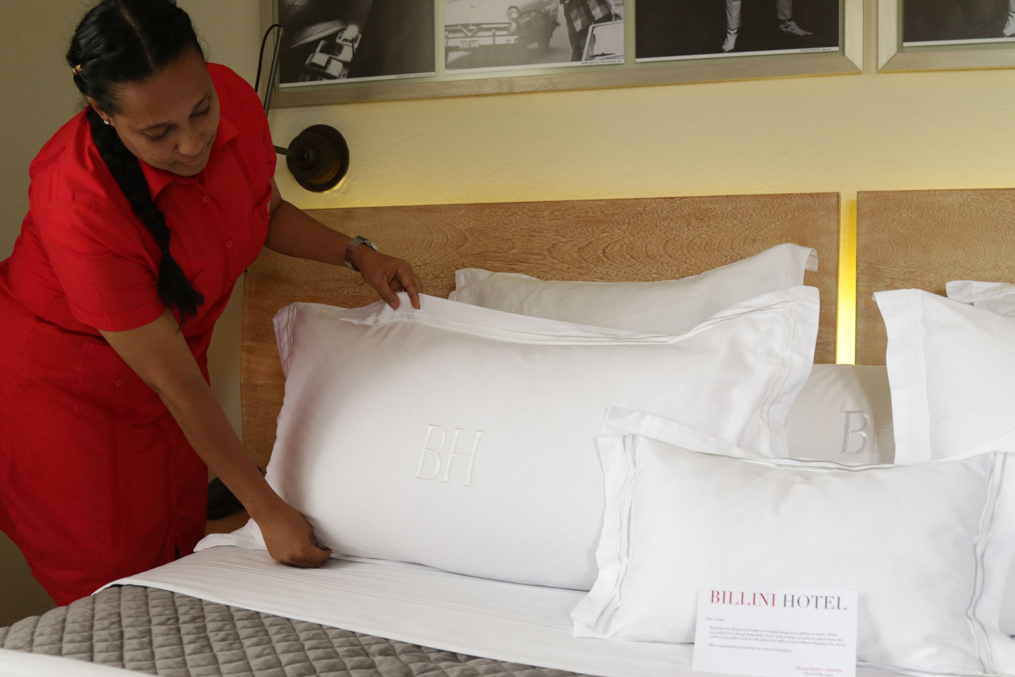 Quarto de hotel com cama bem arrumada, uma placa indicando 'BILLINI HOTEL' e uma moldura com uma imagem na parede.